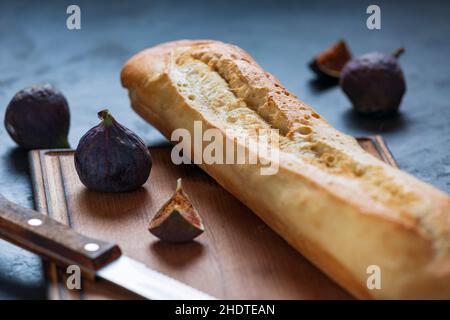 Fresh baguette with crispy crust and fruits of ripe figs on the table ...