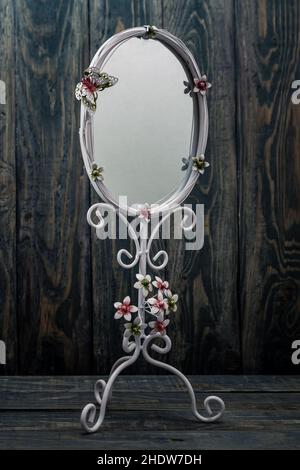 Vertical shot of a vintage mirror with decorative border against a ...