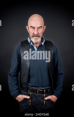 Vertical serious confident bearded carpenter in protective coveralls ...