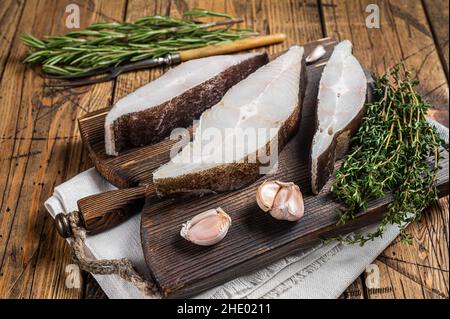 Atlantic halibut fish, raw steaks on wooden board with herbs. Wooden ...