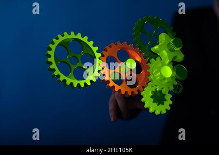 Male's hand holding an illustration of green metallic gears and cogs ...