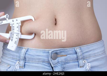 Subcutaneous fat on belly of woman 28 years old who stands near mirror ...