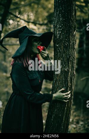 attractive woman in witch hat and wig holding magic wand in Halloween ...