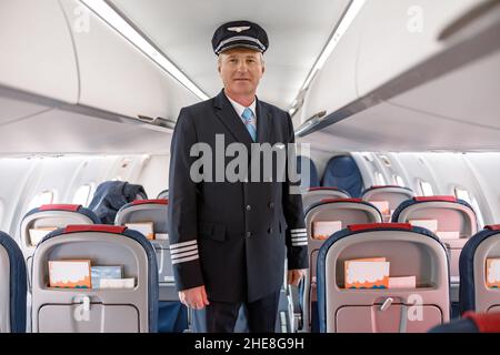Male pilot standing in passenger airplane cabin Stock Photo - Alamy