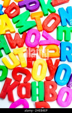 Colorful alphabet and number magnets scattered on a white surface ...