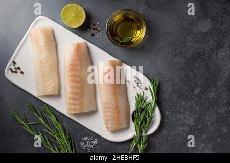 Raw cod loin fillet steak on wooden board with butcher cleaver. Dark ...