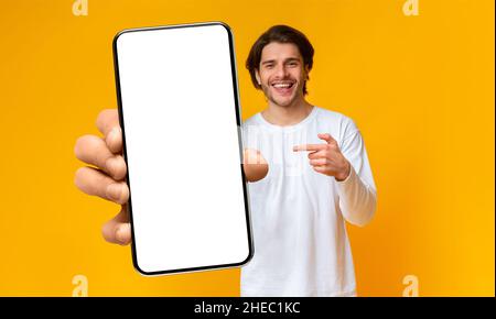 Positive millennial man showing huge brand new smartphone with empty ...