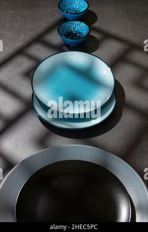 Tableware, different plates in grey blue colors on dark table with ...
