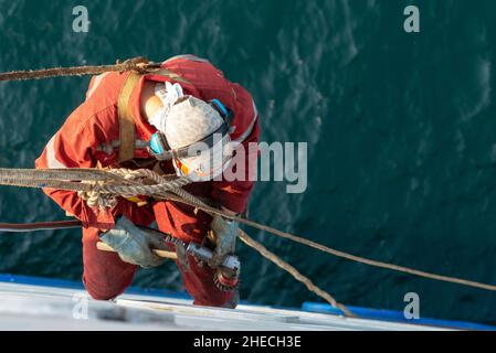 Seaman ship crew working aloft at height derusting and getting vessel ...