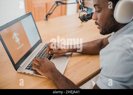 African man recording a podcast using microphone and headphones from ...