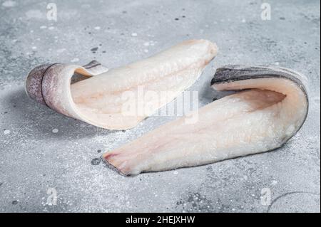 Two raw haddock fish fillets on kitchen table. Gray background. Top ...