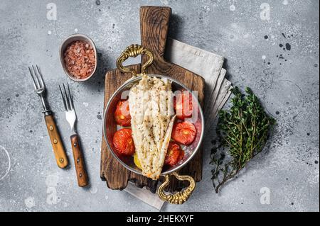 Roasted Haddock fish fillet in skillet with tomato and potato. Gray ...