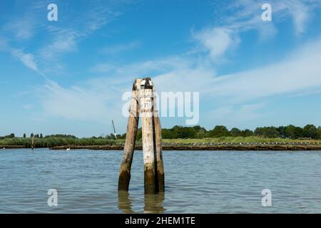marker for the waterway at the lagoon in Venice under blue sky with ...