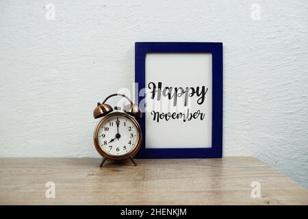 Happy November typography text with alarm clock and artificial plant ...