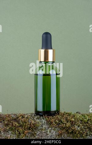 Cosmetic dropper bottle with green moss, cucumber and rocks on color ...