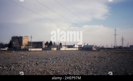 Deserted area with ugly buildings and electricity transmission pylons ...