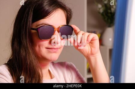 A woman in perforated glasses looks at the computer screen Stock Photo ...