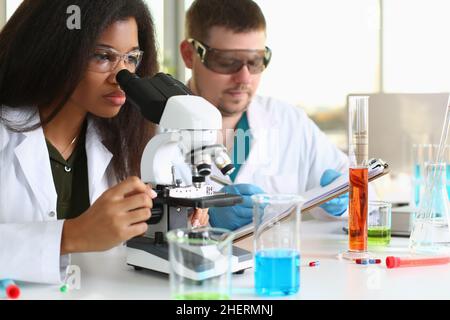 Two chemistry students conduct microscopic examinations in laboratory ...