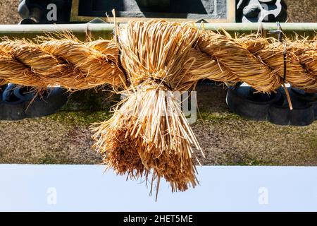 Japanese twisted knotted straw rope on top of massive sake barrel left ...