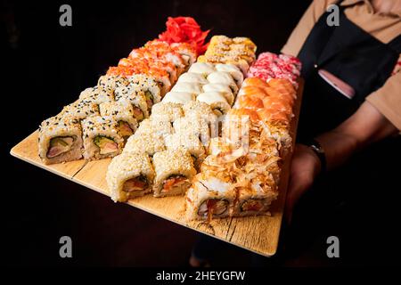 Waiter holding a set of sushi rolls on a plate. Close-up, selective ...