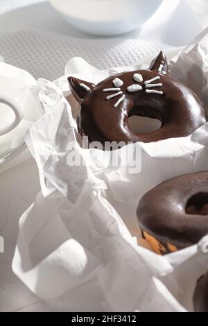 Homemade chocolate donuts in a white paper packaging with a donut in ...