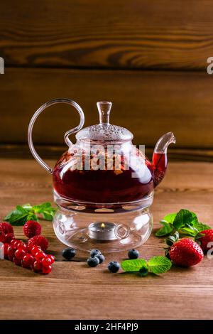 Fruit and berry tea in teapot. Hot drink with lemon, mint, blueberry ...