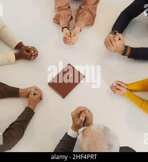 Diverse group of people praying to Lord sitting together around table ...
