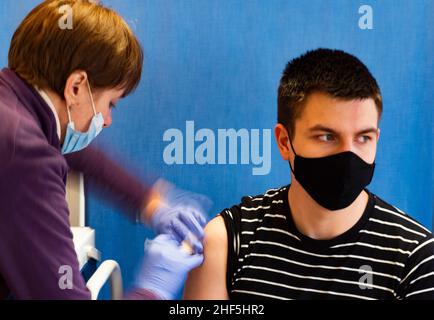 A man receives a dose of the Pfizer COVID-19 vaccine, at a vaccination ...