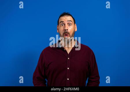 Hispanic man standing over pink background with hand on stomach because ...