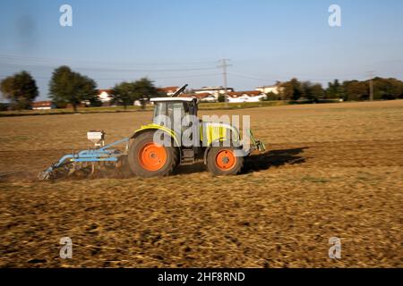 traktor is running on the acre plowing the earth in golden light and ...