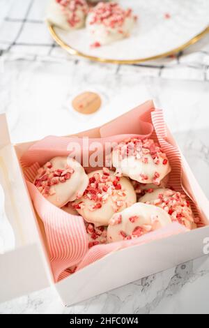 Packing freshly baked peppermint white chocolate cookies into a white ...