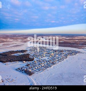 Rural timber houses and barns are on winter lake shore. Russian remote ...