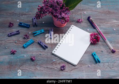 Blank notebook, pencils, lilac flowers and colorful pegs on vintage ...