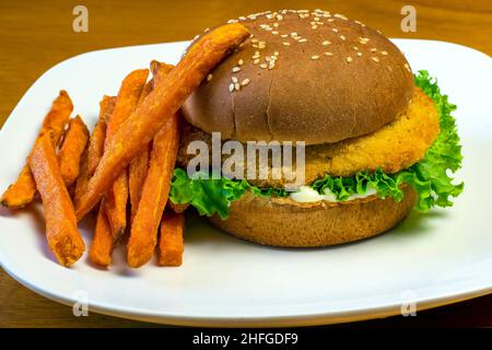 chicken fillet on a sesame bun and served with a side of fries Stock ...