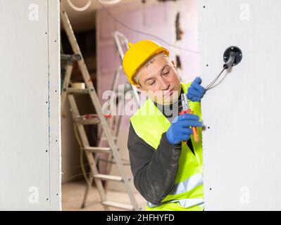 Electrician mounting electrical wiring inside building in process of ...