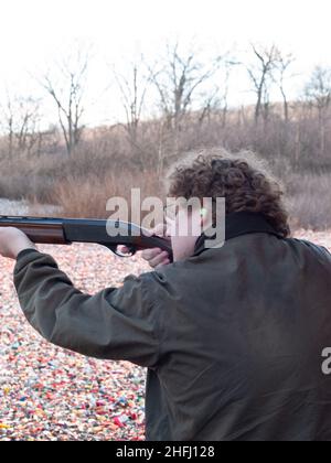 A young man shooting sporting clays with a shotgun at a shooting range ...