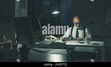 Old businessman employee working overtime at workplace Stock Photo - Alamy