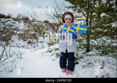 Scandinavian baby girl with Sweden flag in winter swedish landscape ...