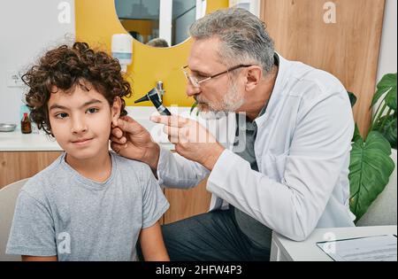 Audiologist examining child's ear with otoscope. Otoscopy and hearing ...