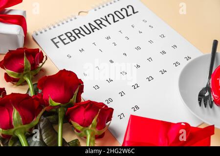Calendar with roses, gift boxes and dessert on beige background ...
