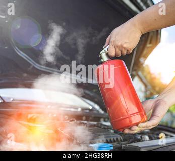 The driver of the car directs a powder fire extinguisher at the engine ...