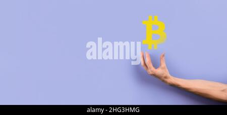Male hand holding a bitcoin icon on blue background. Bitcoin ...
