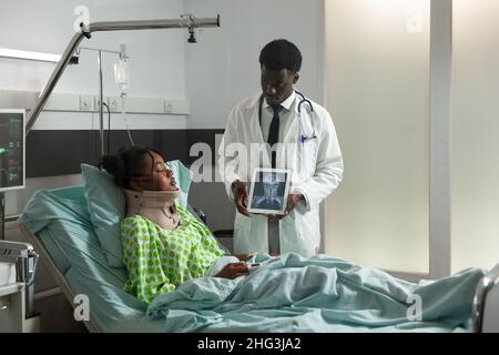 Specialist explaining radiography to woman with neck collar in hospital ...