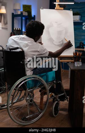 Young man with disability drawing vase design at art class lesson ...