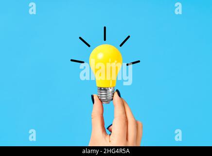 Female hand hold yellow light bulb on blue background Stock Photo - Alamy
