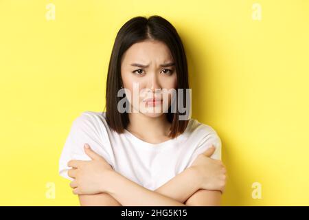Sad timid girl comforting herself, hugging body and frowning upset ...