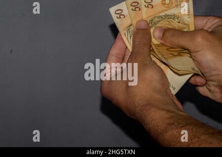 Fifty real note with hand holding, brasilian money, dark background and ...