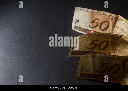 Fifty real note with hand holding, brasilian money, dark background and ...