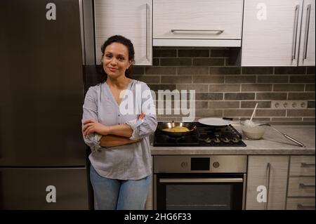 Pretty housewife smiling cutely at camera, holding a mold with rolled ...