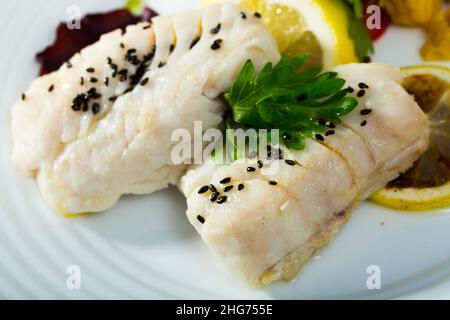 Cod prepared on steam, served at plate with greens and lemon Stock ...